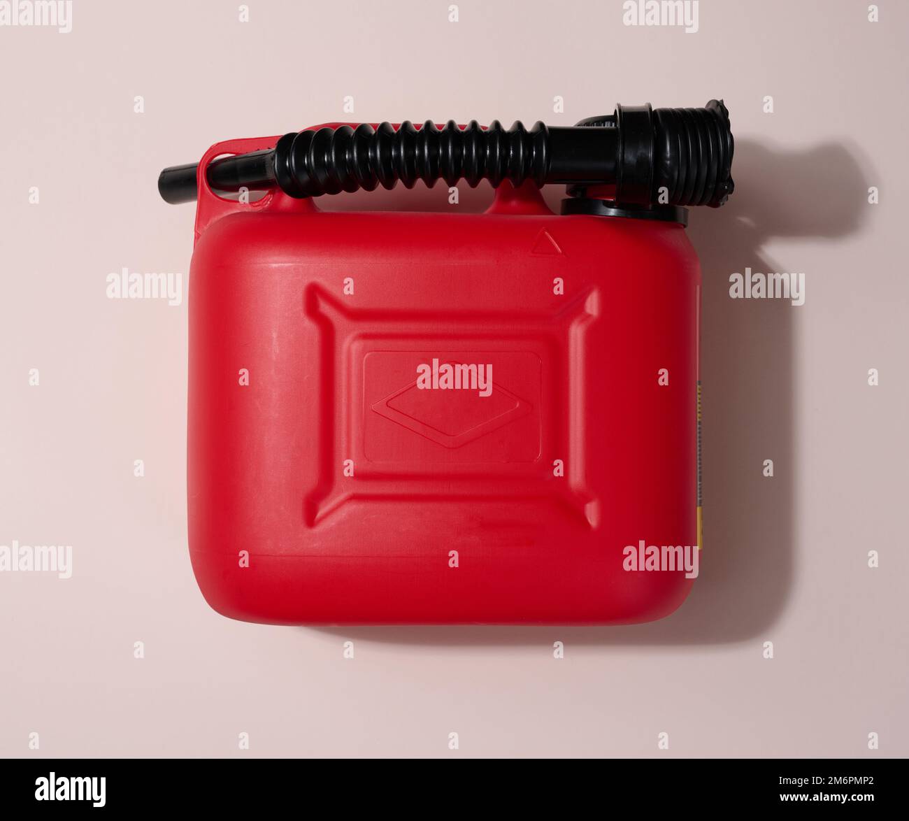 Red plastic canister for liquid fuels and lubricants on a beige ...