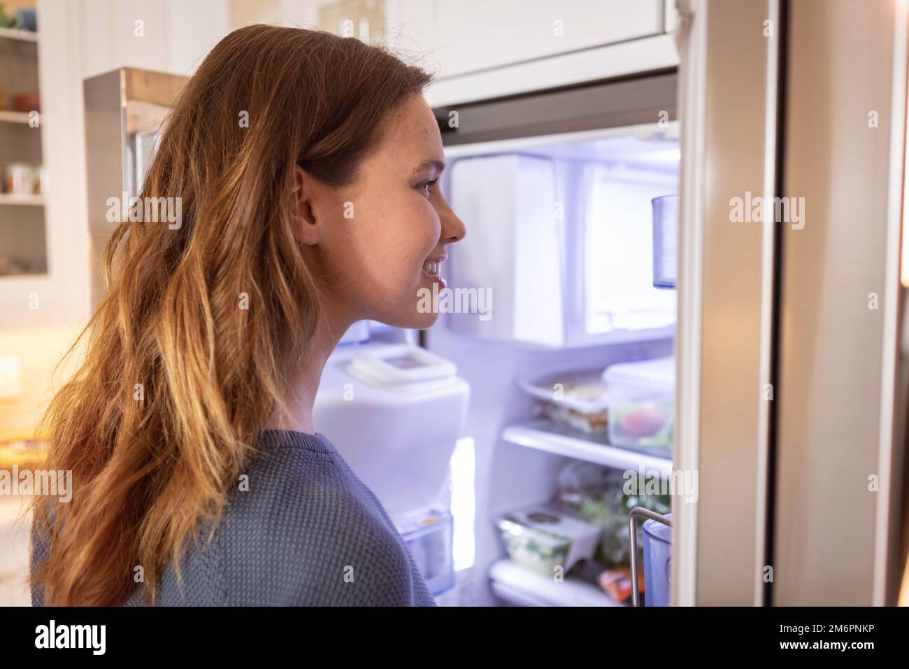 Woman opening the fridge at home Stock Photo - Alamy