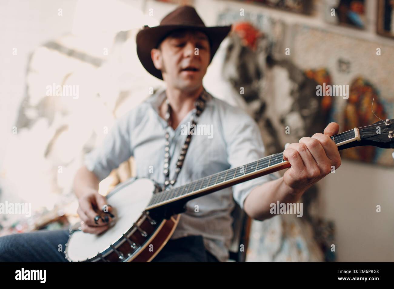 Male musician playing banjo sitting chair indoor Stock Photo - Alamy