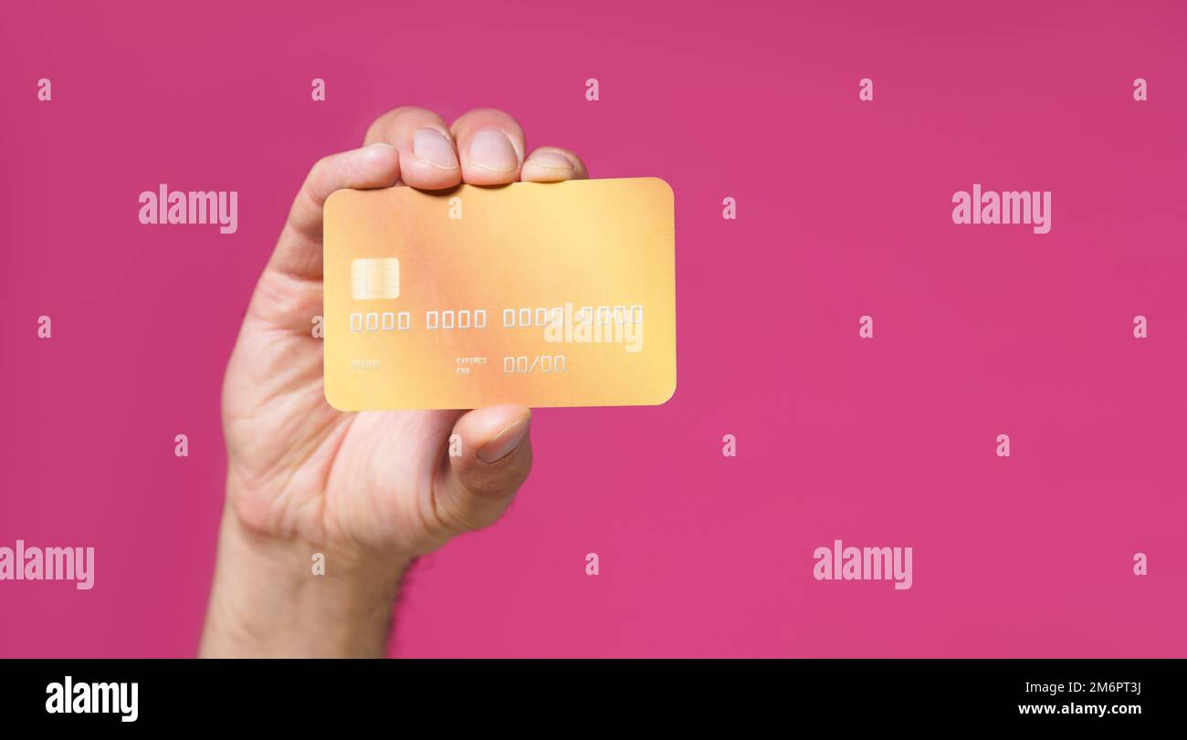 Close up yellow debit, credit card in man hand isolated on pink ...
