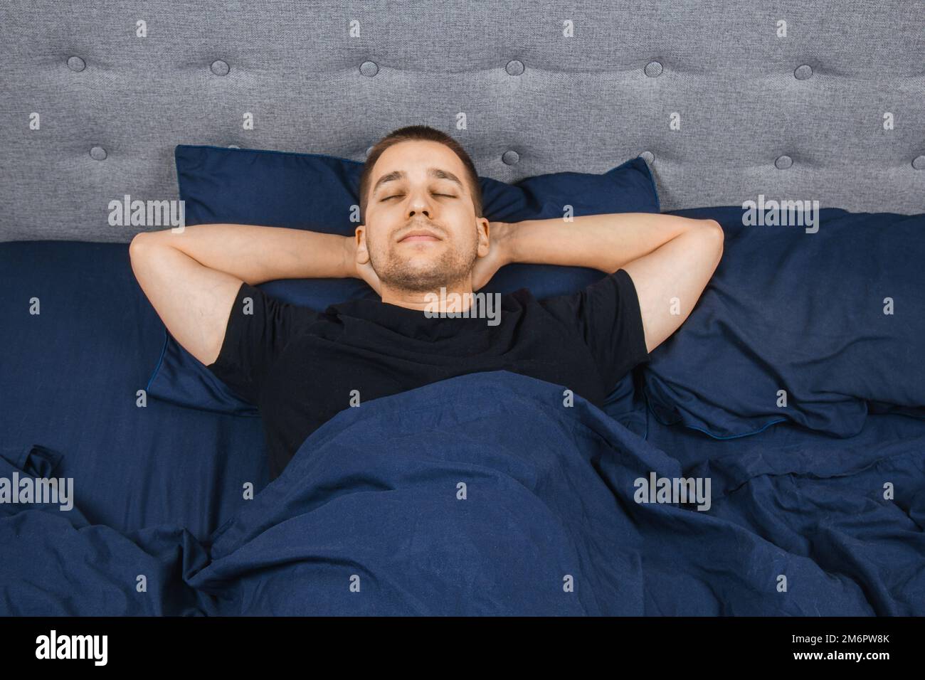 Top view of a handsome young man sleeping comfortably on the bed in his ...