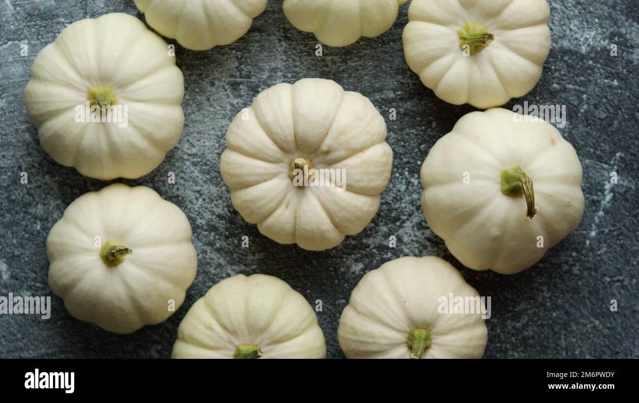 Small white Baby boo mini pumpkins placed in circle on dark stone table ...