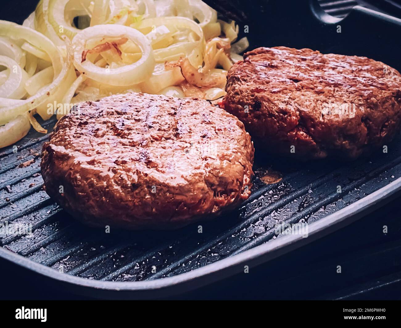 Cooking minced beef burger on cast iron grill skillet outdoors, red ...