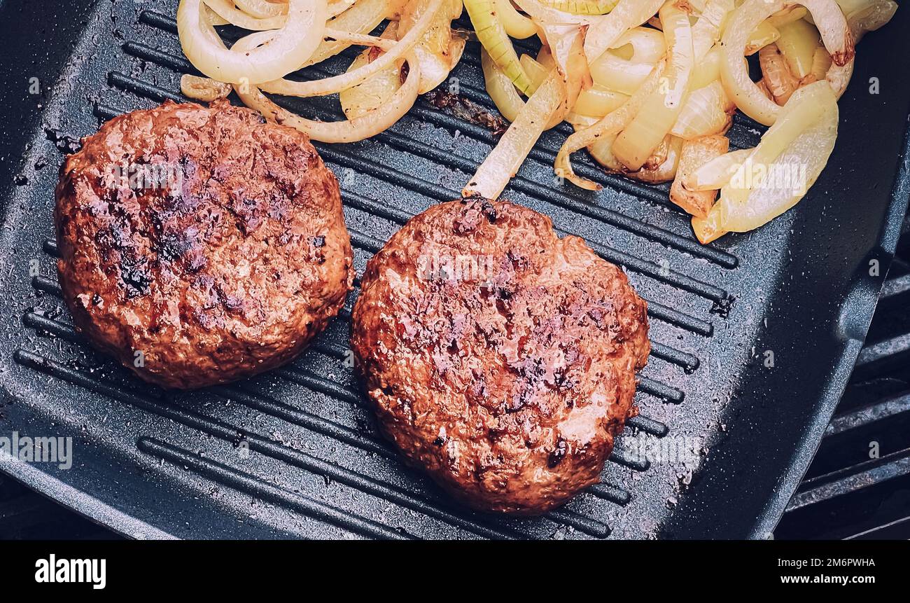 Cooking minced beef burger on cast iron grill skillet outdoors, red ...