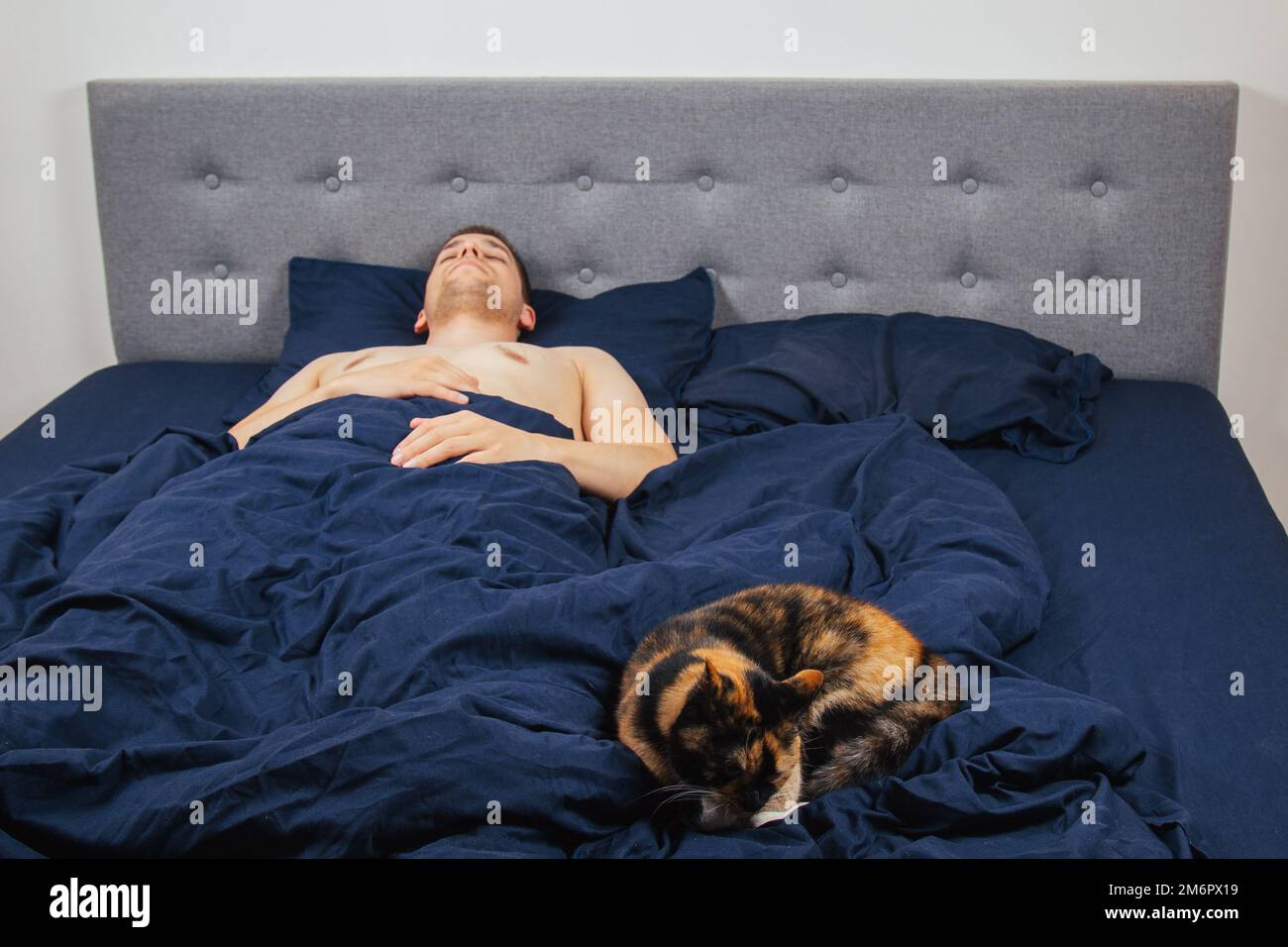 Side view of a handsome young man sleeping comfortably on a bed at ...