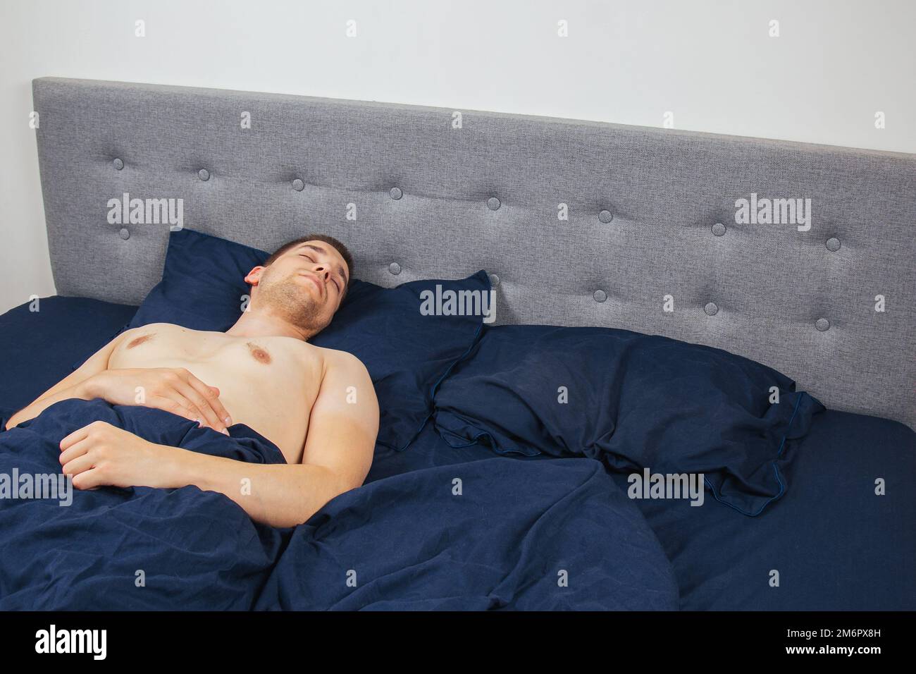 Handsome young man sleeping comfortably on the bed at night in his ...