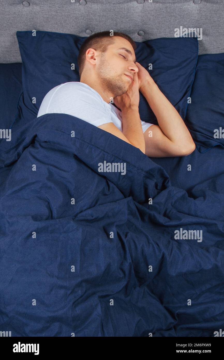 Top view of a handsome young man sleeping comfortably on the bed at ...