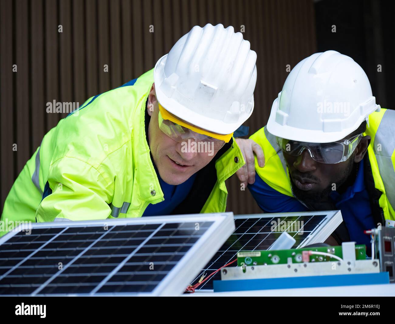 Two professional solar cell engineers wearing safety vest and hardhat ...
