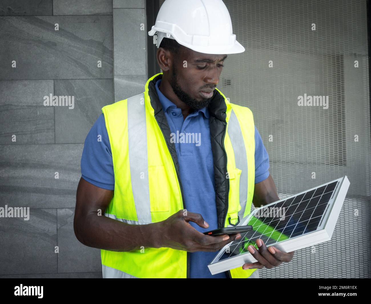 African American solar energy engineer using a smartphone to check ...