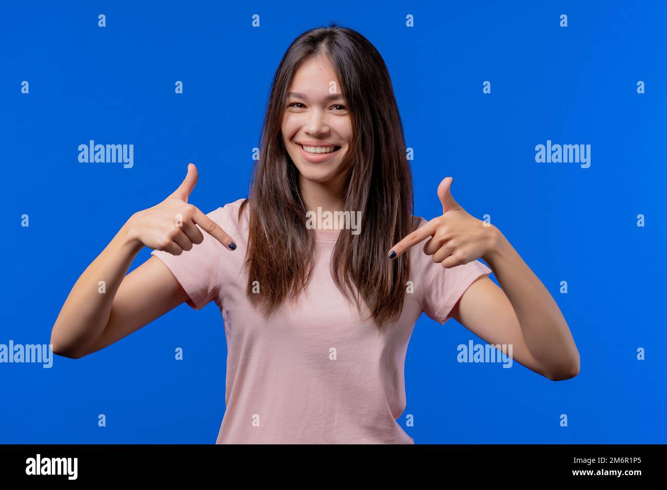 Pretty teenager pointing down to advertising area. Blue background ...