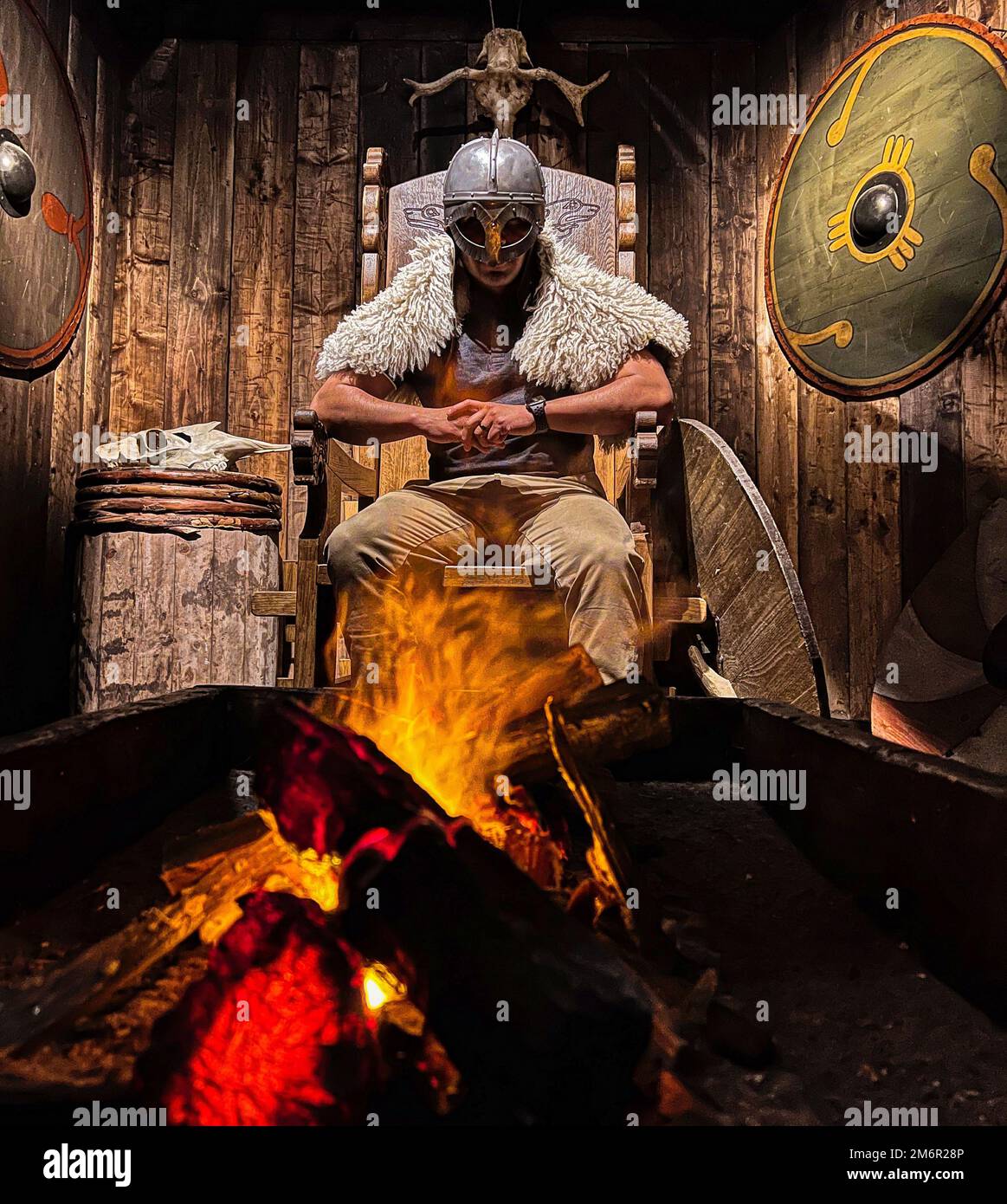 A historical warrior with a helmet sitting on the throne by the fire ...