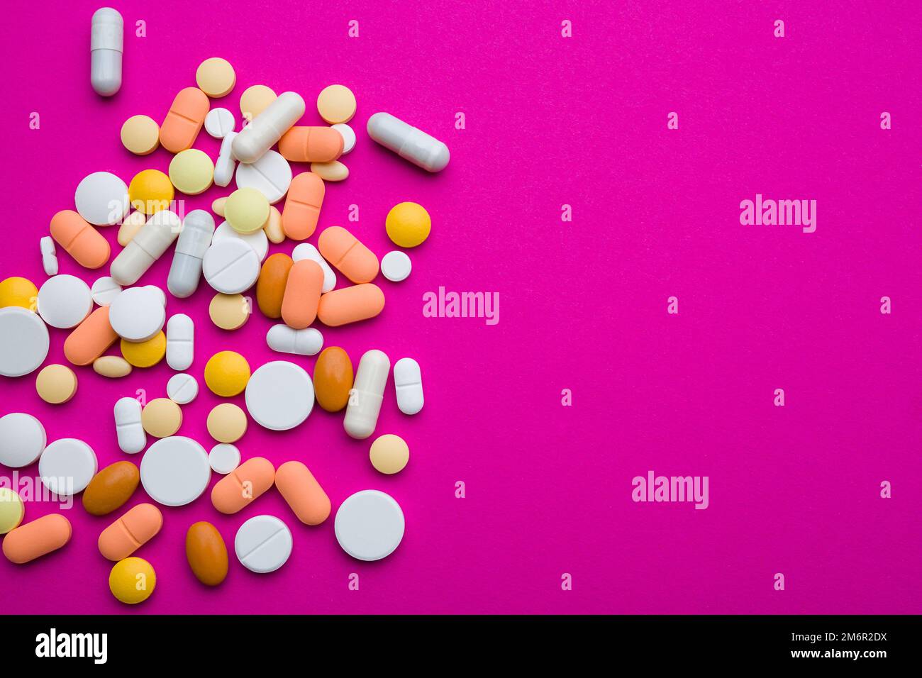 Assorted pharmaceutical medicine pills, tablets and capsules on magenta ...