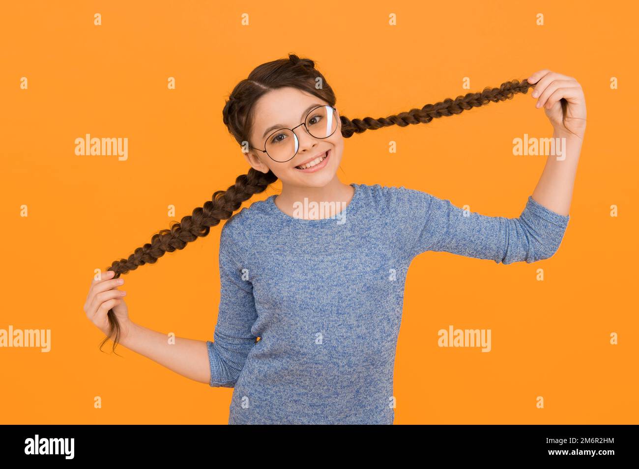 Interested in my hair and my hairdresser. Happy girl hold hair braids ...