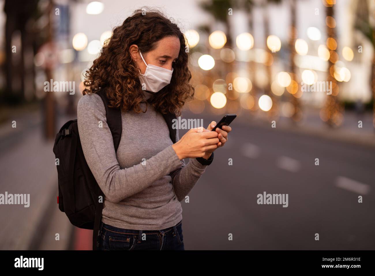 Caucasian woman wearing a protective mask and using her phone in the ...
