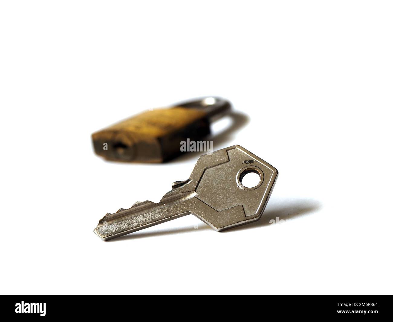 Metal key in front of blurred padlock Stock Photo - Alamy