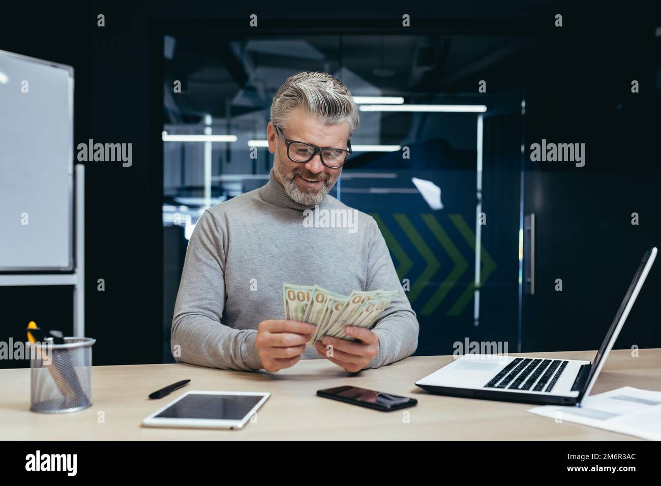 Mature successful financier investor counts money dollars cash sitting ...