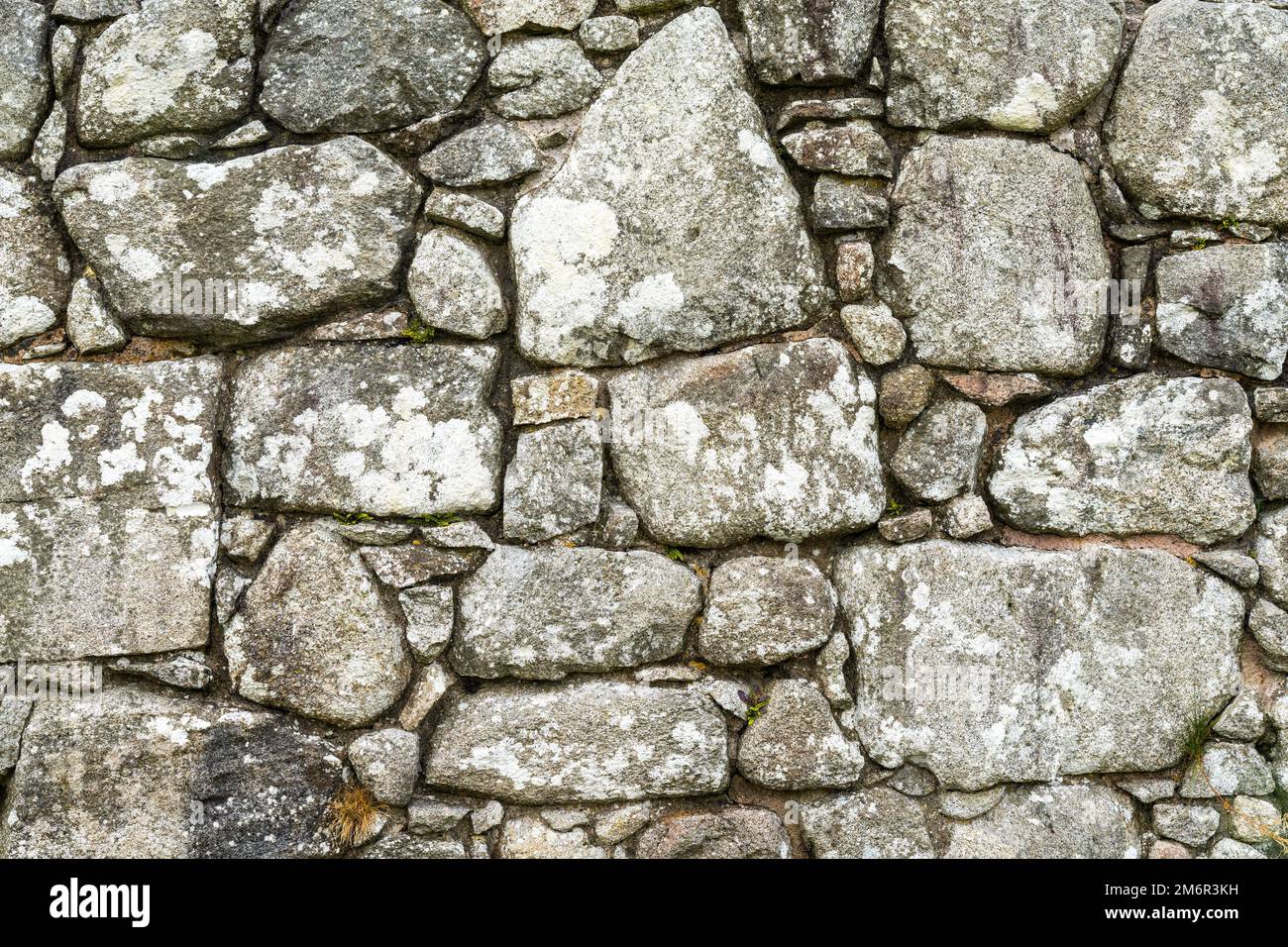 A background of an old stone wall built with uneven and random blocks ...