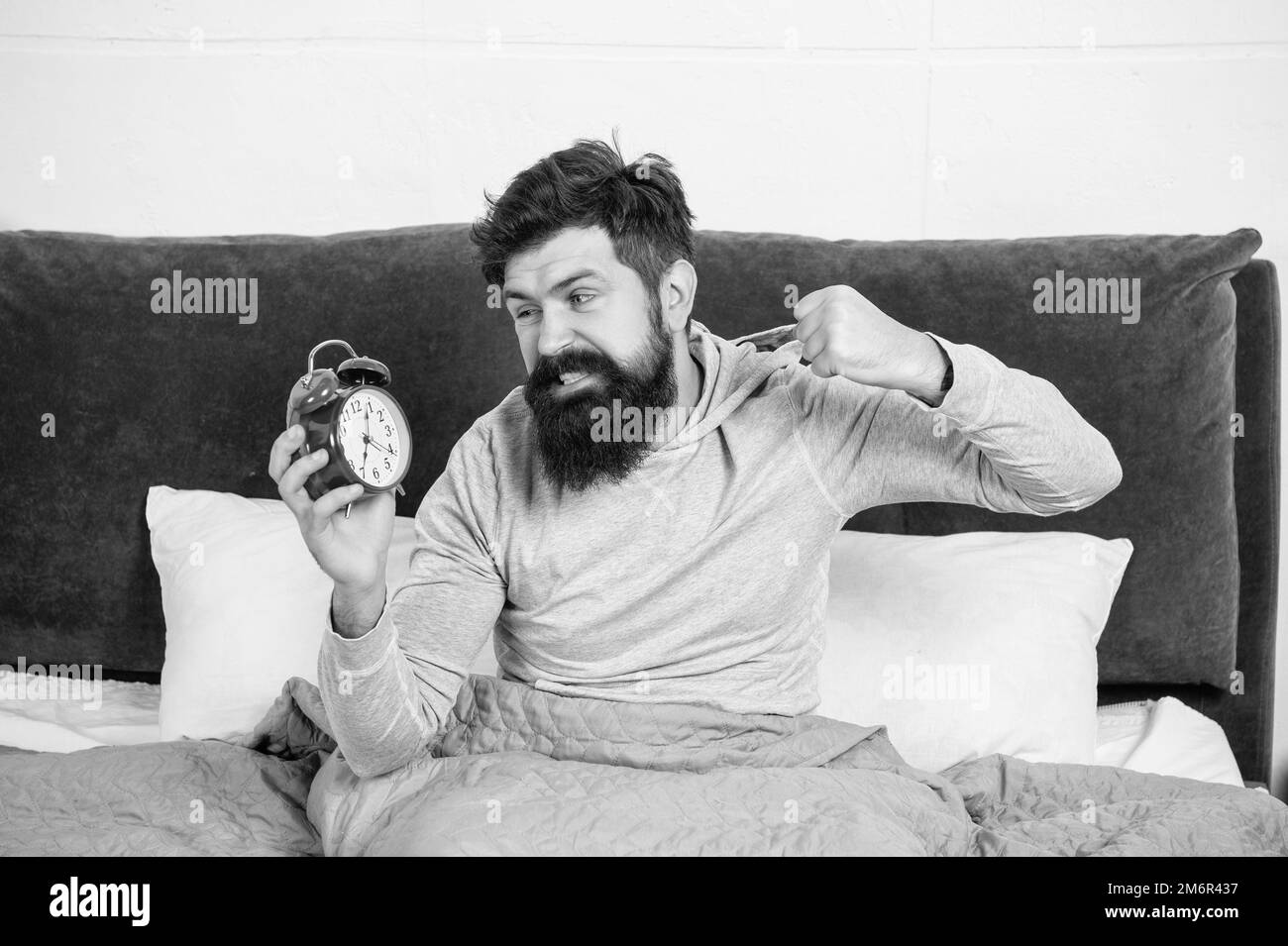 Angry man punching alarm clock being in bed in morning, overslept Stock ...