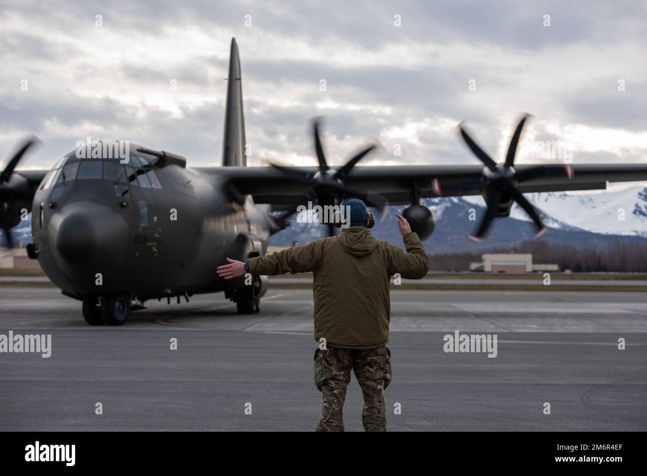 A Royal Air Force mechanic marshalls a RAF C-130J Hercules, both ...