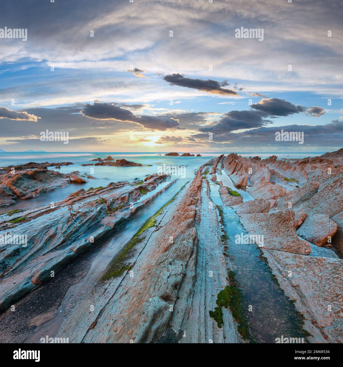 Twilight ocean coast with ribbed stratiform rock Stock Photo - Alamy