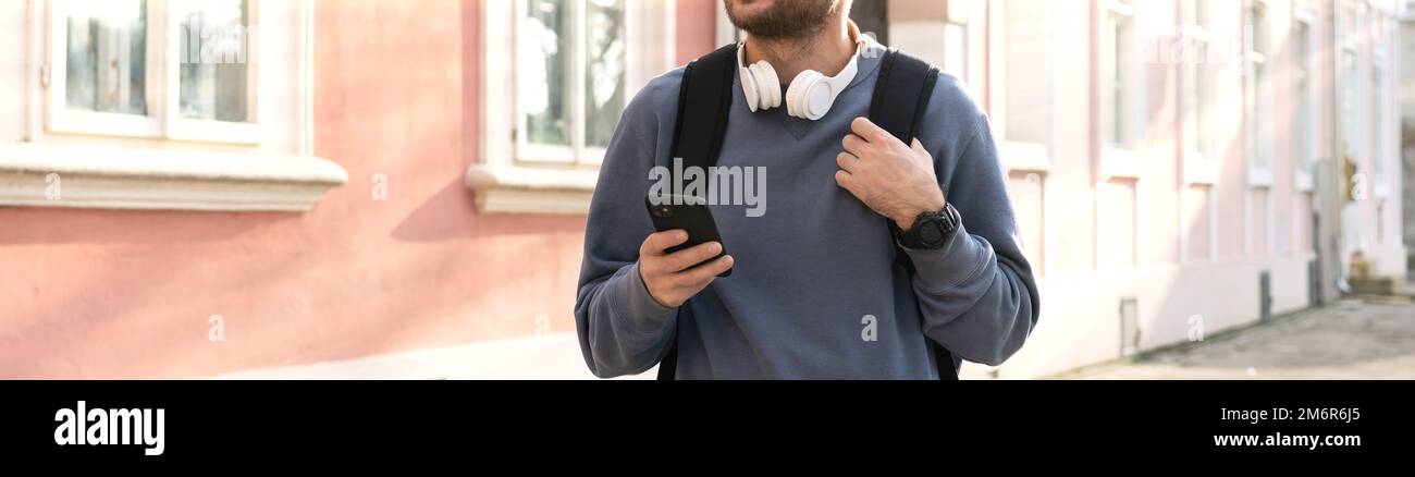 Male person with white headphones on his neck and mobile phone in hand ...