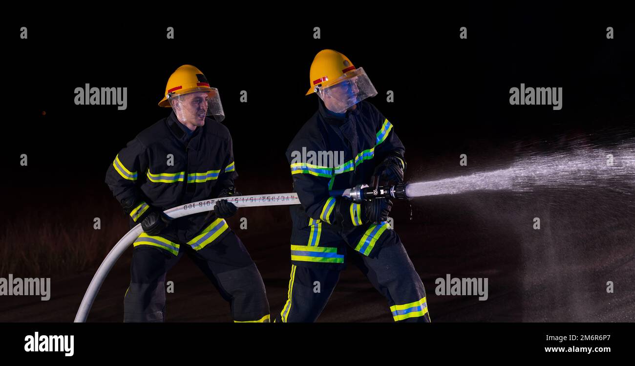 Firefighters use a water hose to eliminate a fire hazard. Team of ...