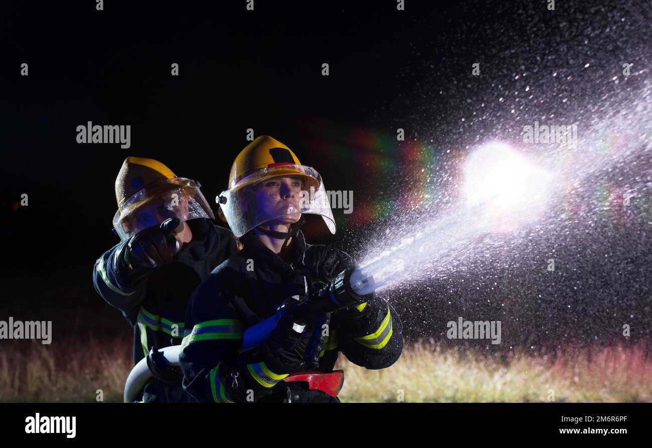 Firefighters using a water hose to eliminate a fire hazard. Team of ...