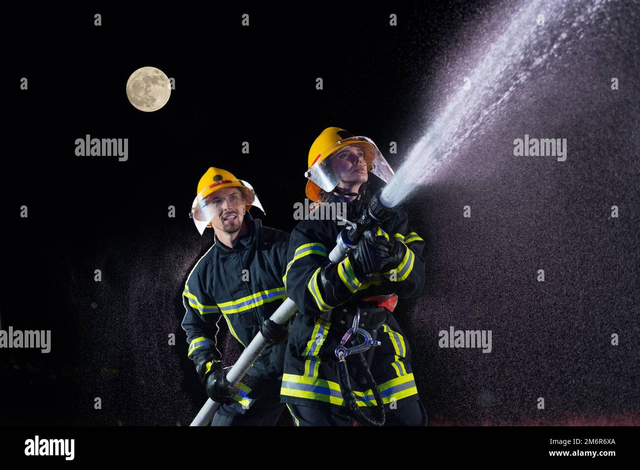 Firefighters using a water hose to eliminate a fire hazard. Team of ...