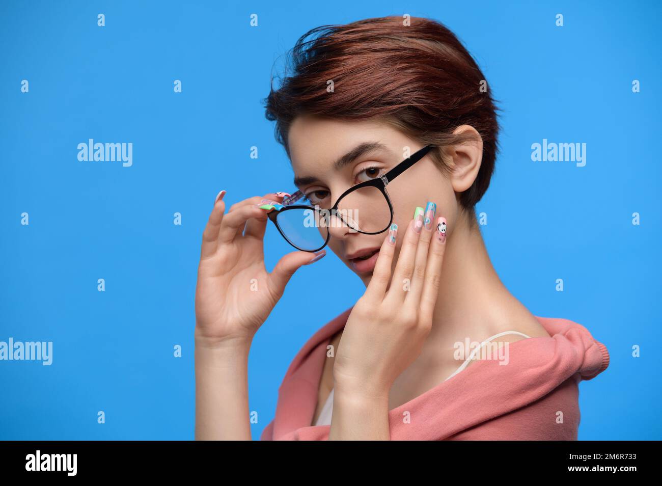 Young girl with short haircut and extravagant nail art looks over the ...