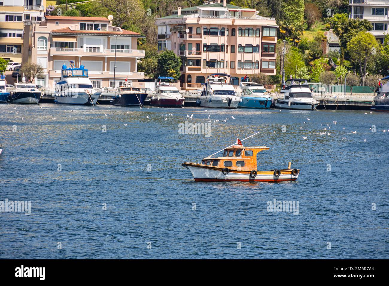 Small fishing ship sailing in front of modern yachts on Bosphorus ...