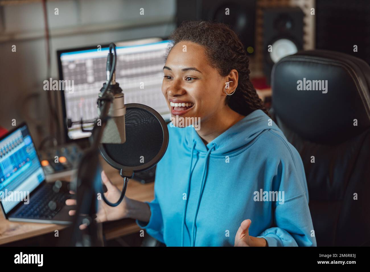 Young African anchorwoman, presenter talking into microphone at radio ...