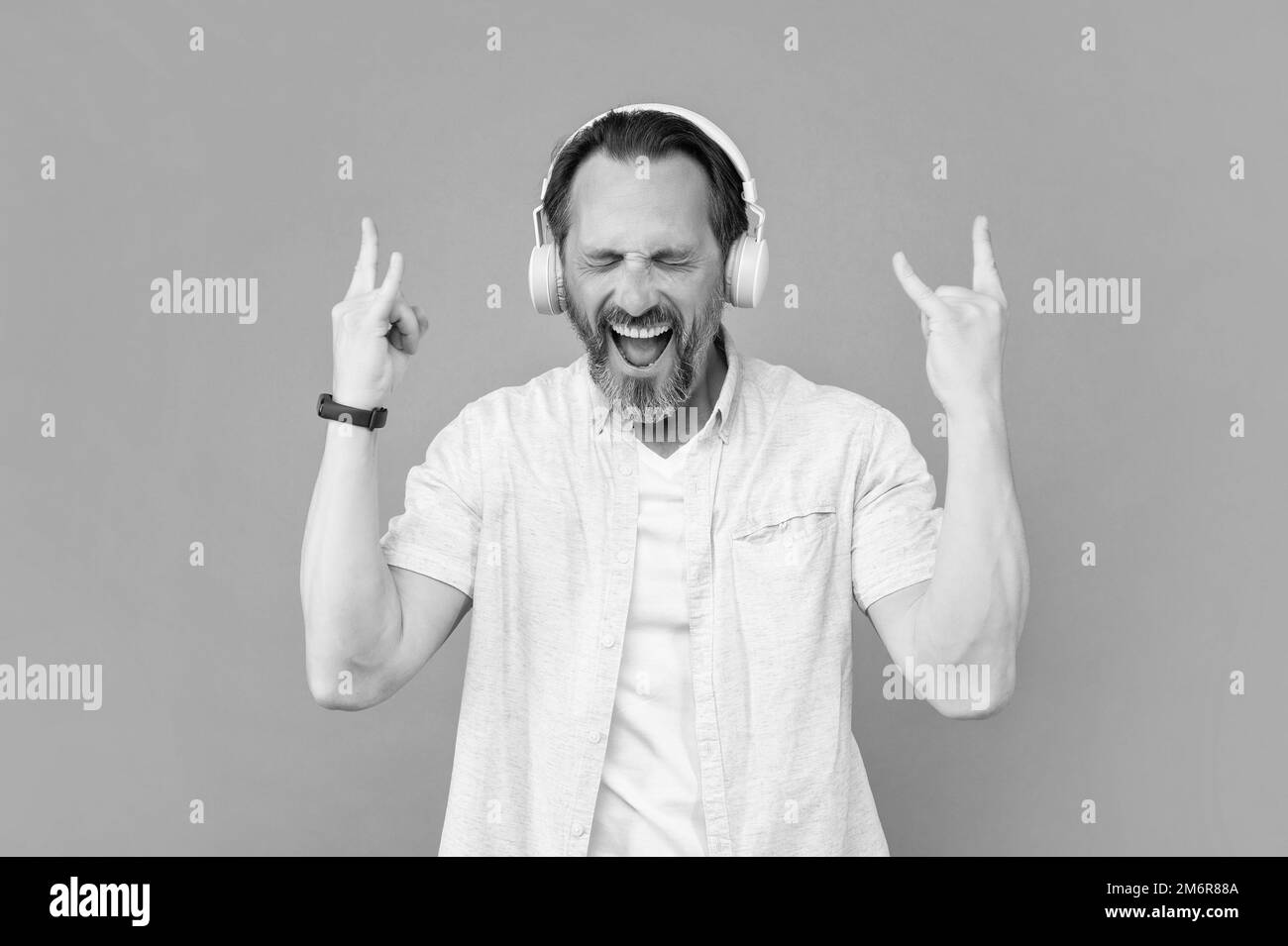 Happy old man sing song listening to rock music in headphones and ...