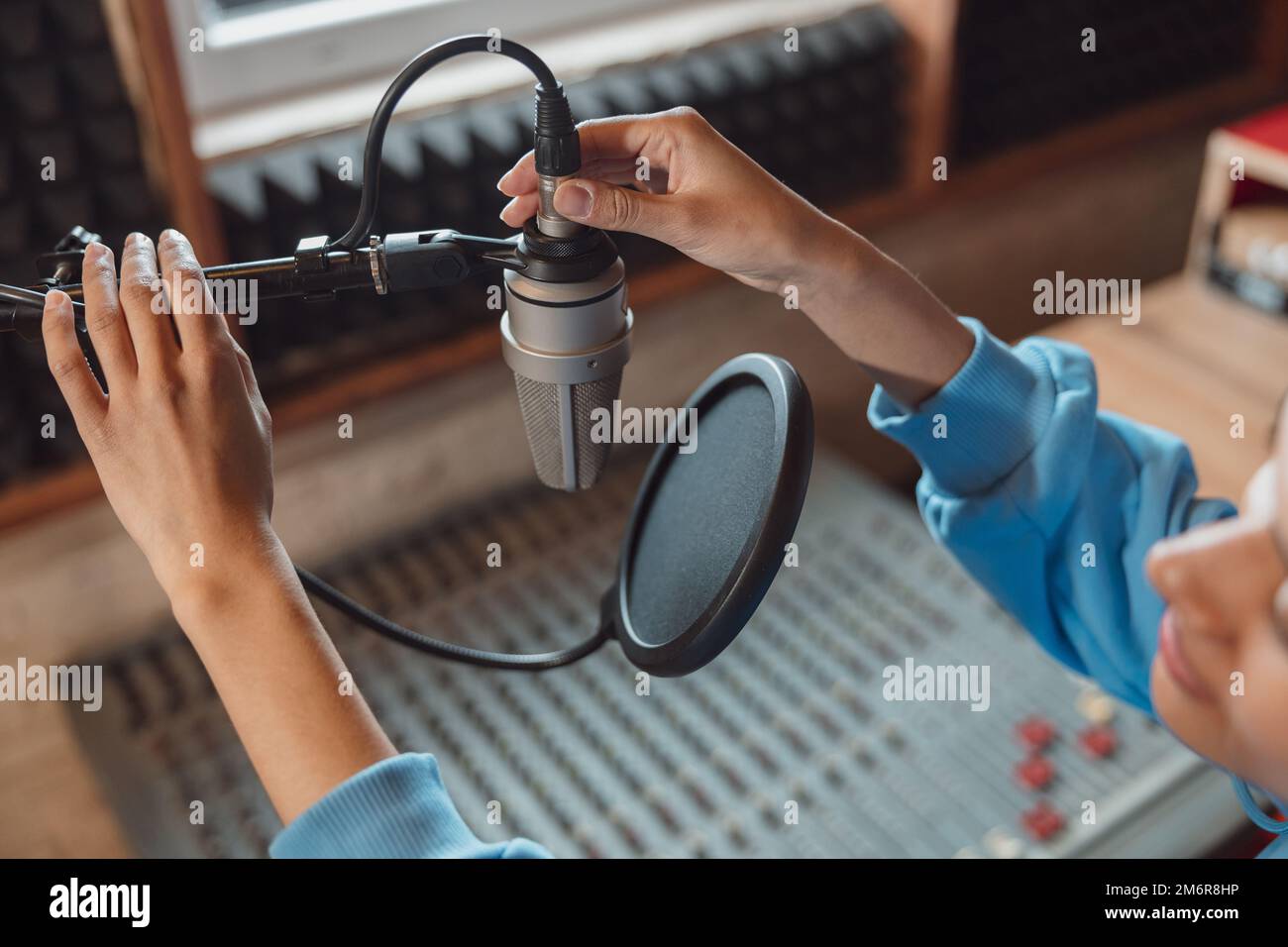 Close-up of audio engineer working in sound record studio, using microphone, mixing board ...