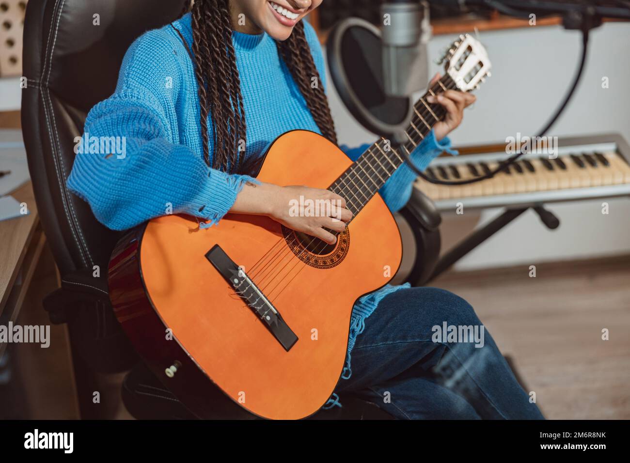 Cropped image of a pretty woman guitarist playing guitar and rehearsing ...