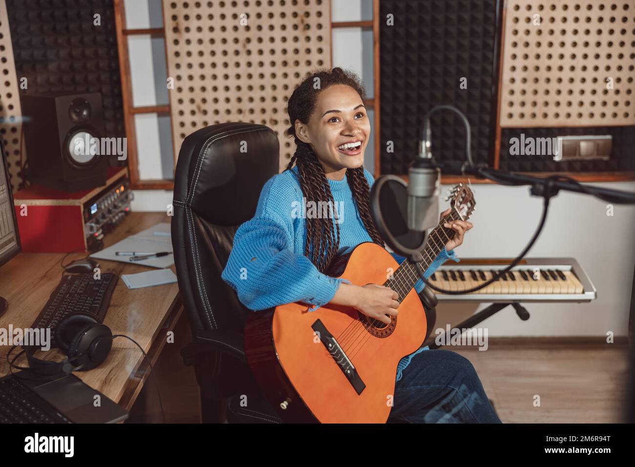 Cheerful talented woman singer playing guitar and singing new cool song ...
