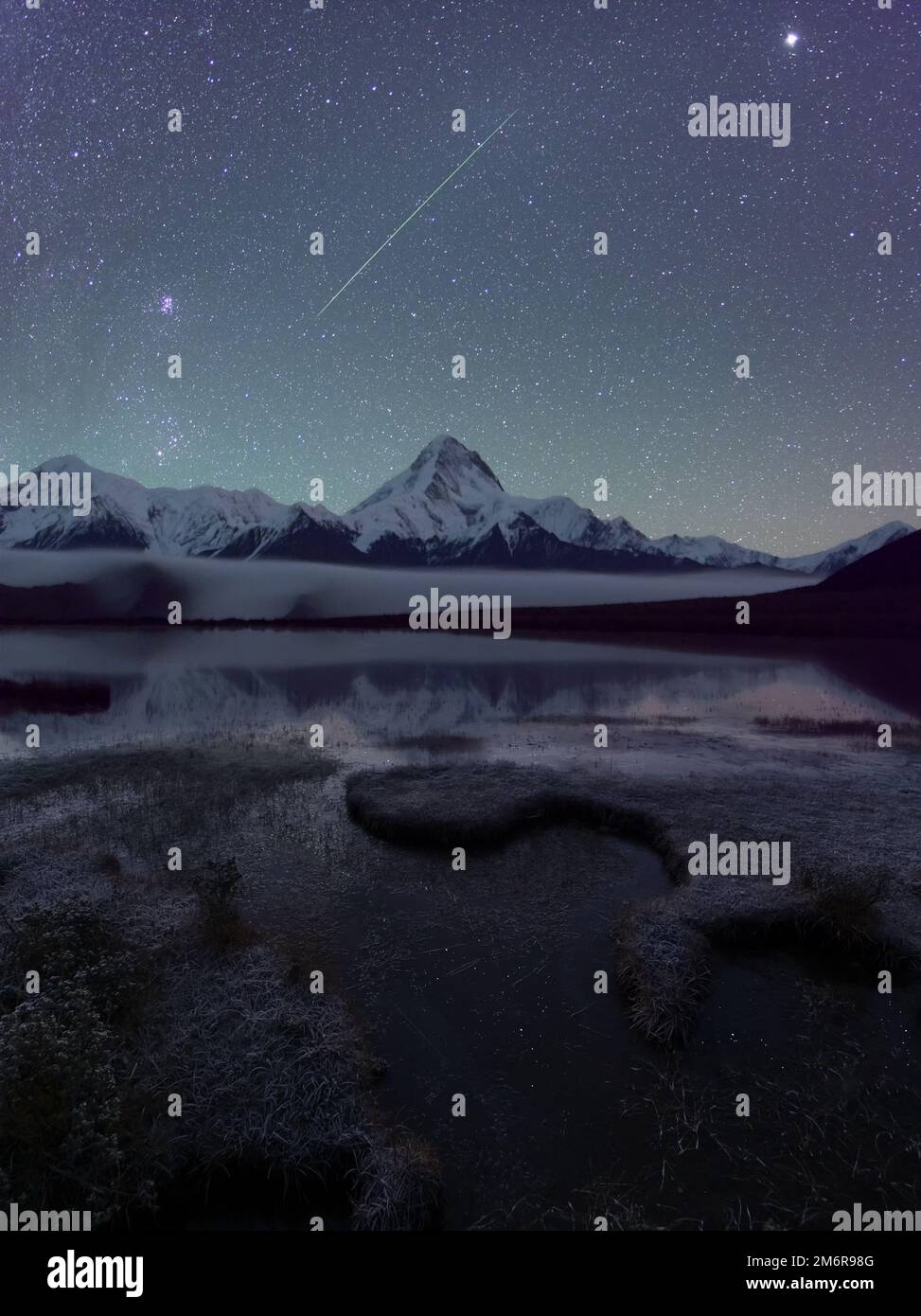 A vertical shot of a starry galaxy night sky with a shooting star over ...