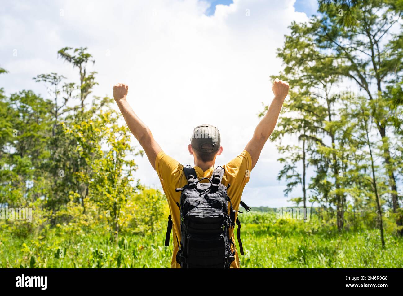 Male traveller with raised hands of happiness in the nature woods ...