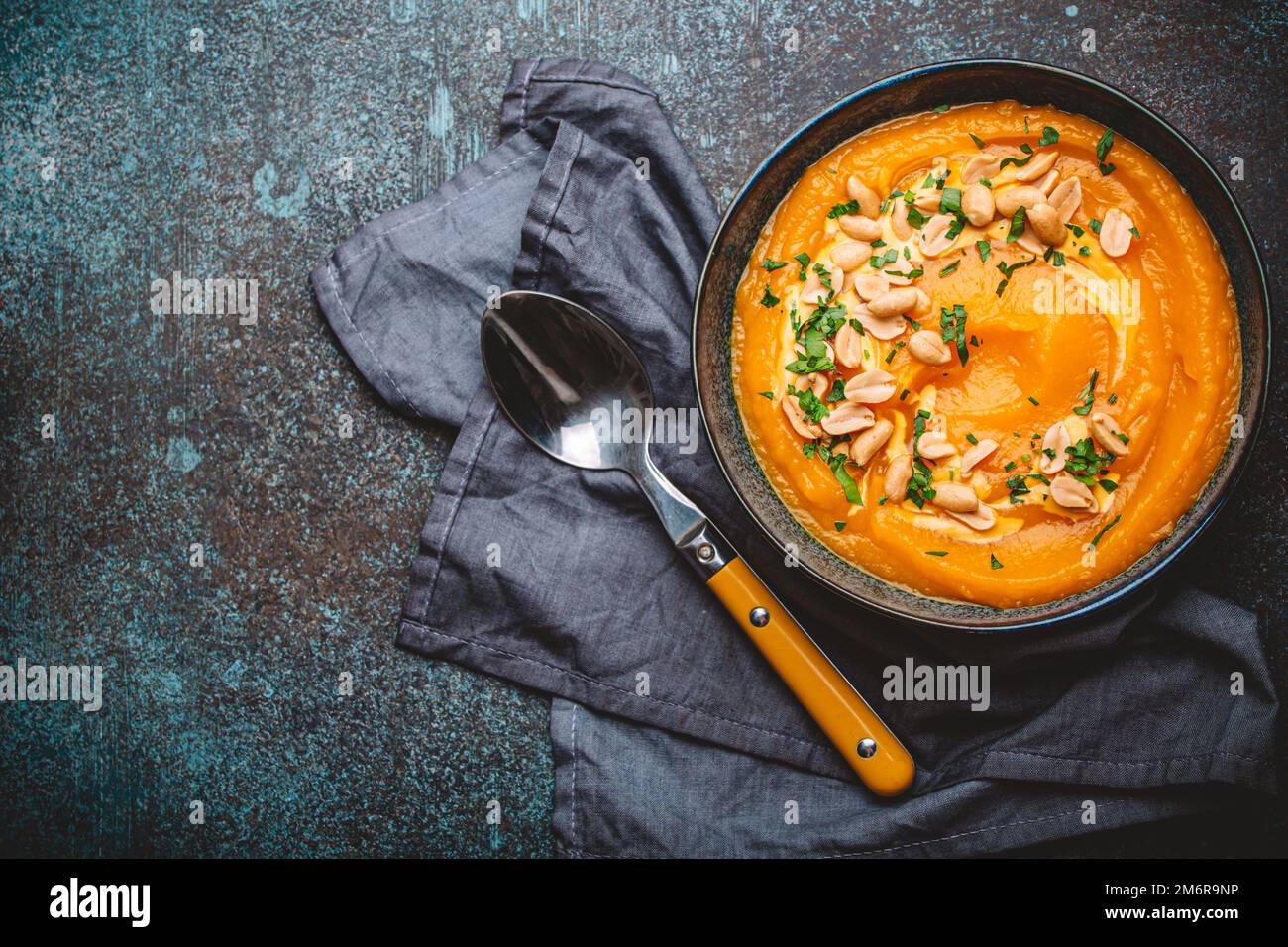 Bowl with pumpkin cream soup with peanuts on dark stone background ...