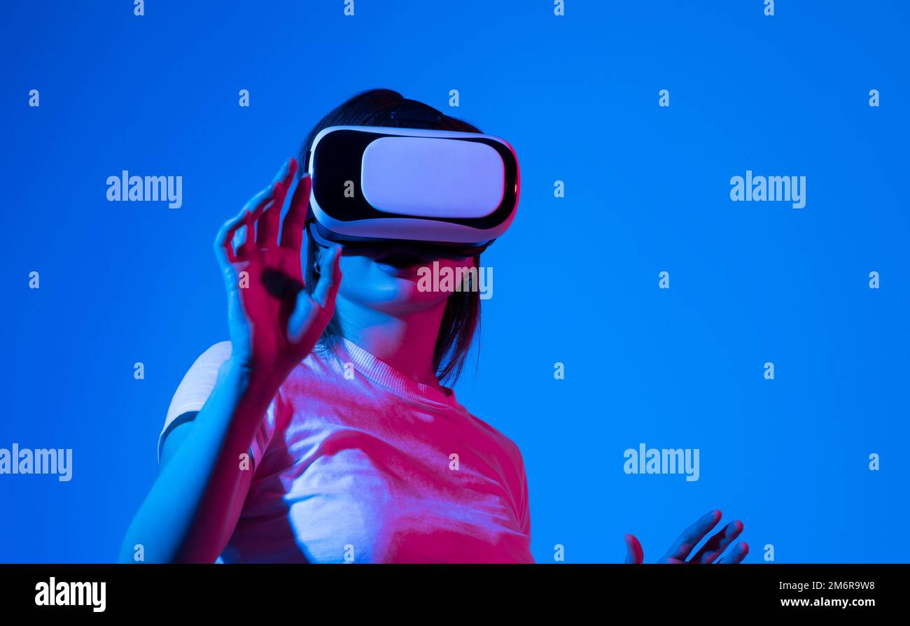Woman in white shirt wearing VR glassess, VR set equipment for exploring a metaverse. Girl ...