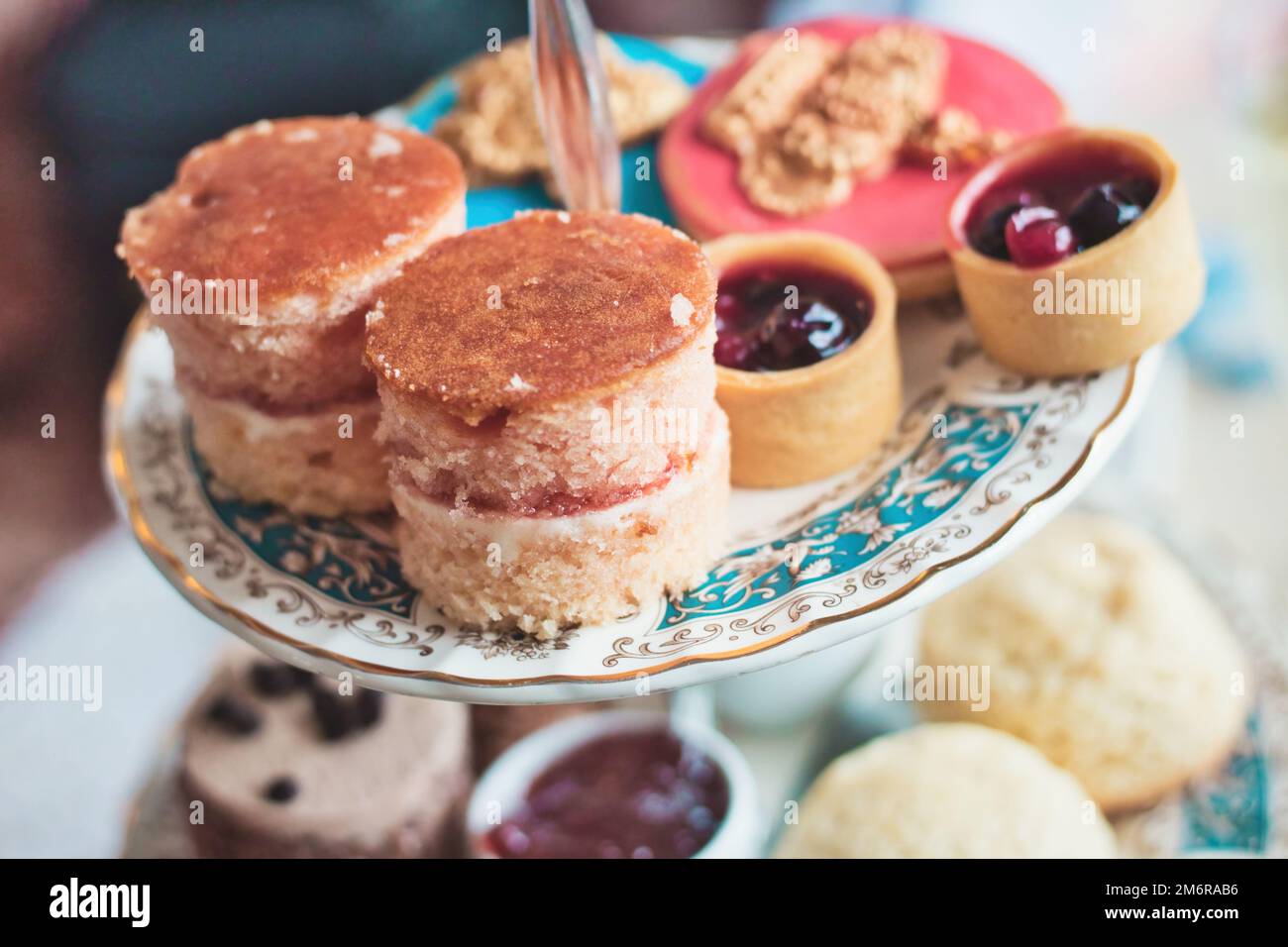 High tea with ceramic tiered plate stand with scones, cupcakes and mini ...