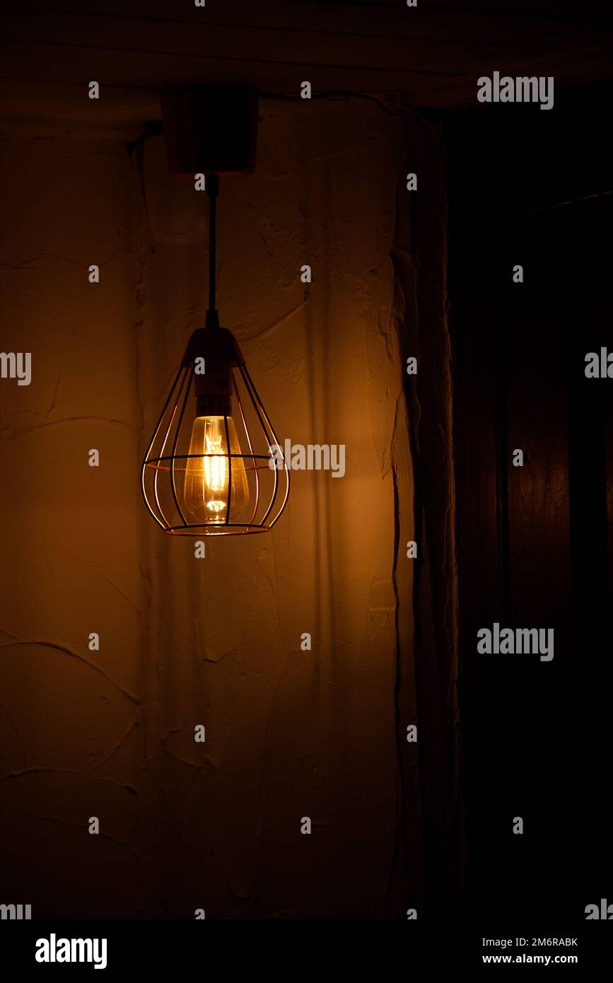 A small atmospheric hanging light with metal covering the bulb slightly ...