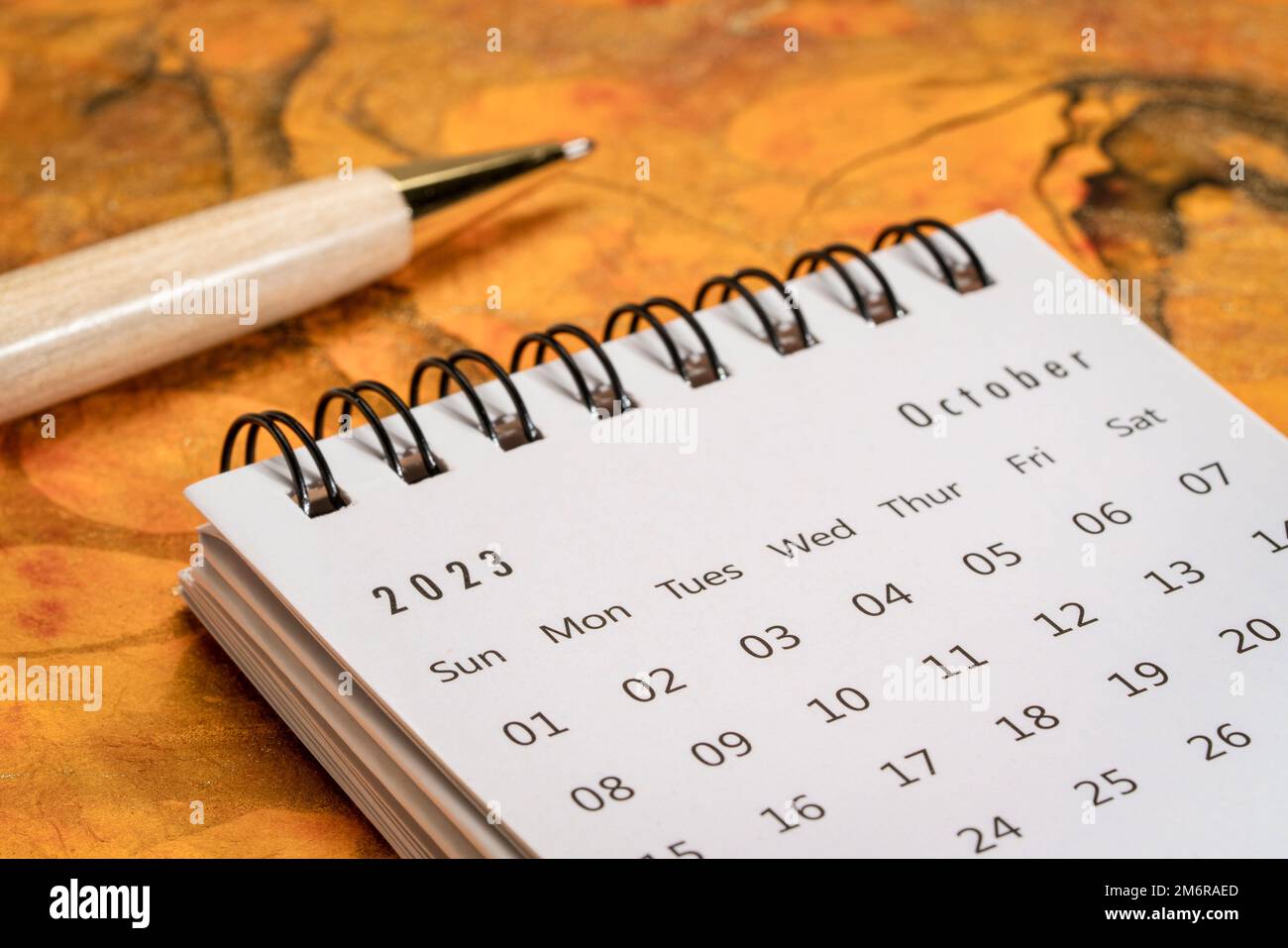 October 2023 - closeup of a small desktop calendar with a pen, time and ...