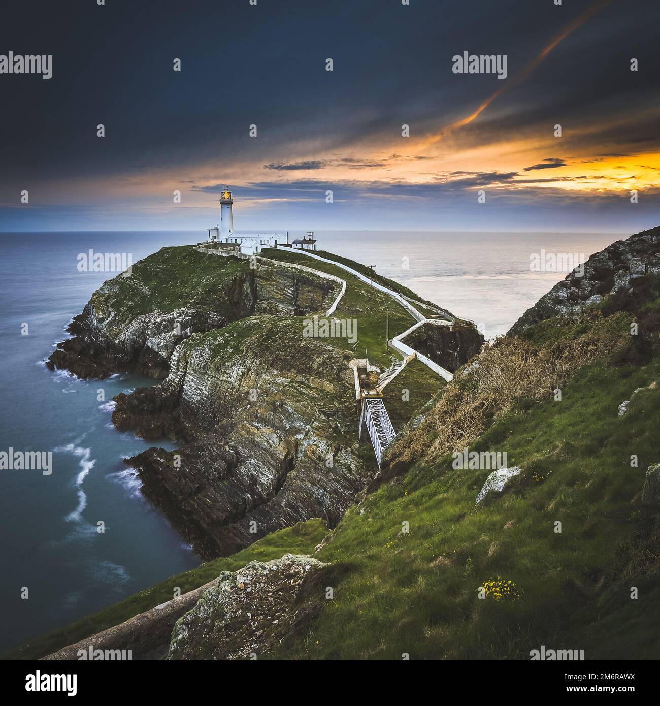 An aerial shot of South Stack Lighthouse on a cliff under the dramatic ...