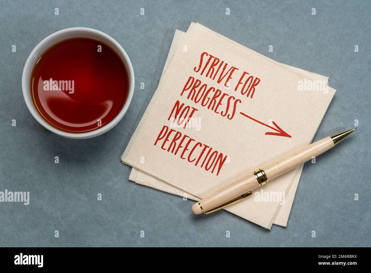 Strive for progress, not perfection - handwriting on a napkin with a tea, success and personal ...