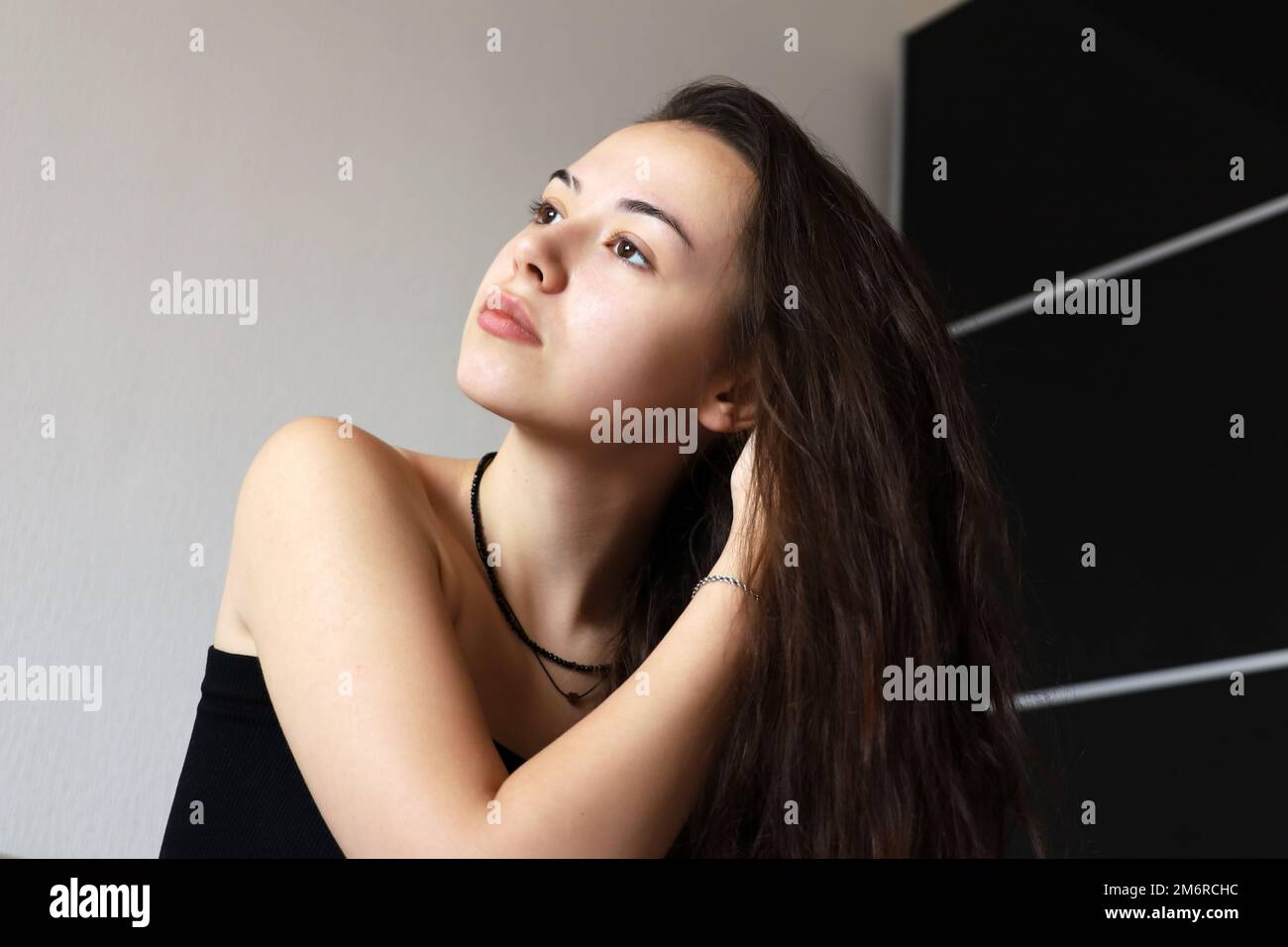 Portrait of attractive young girl with dreamy face expression at home ...
