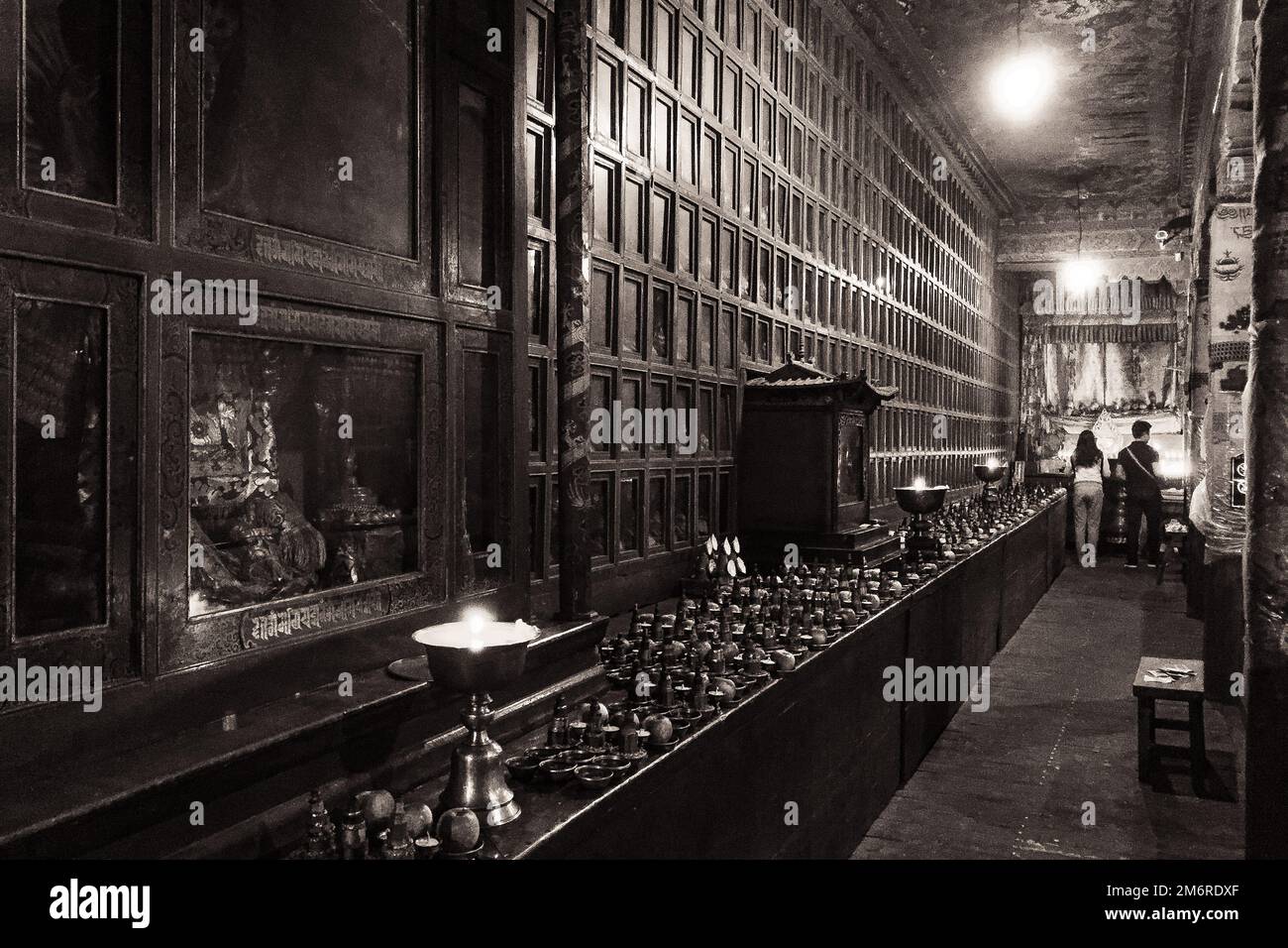 Candles and offerings on a decorated wall of cabinets and figurines ...