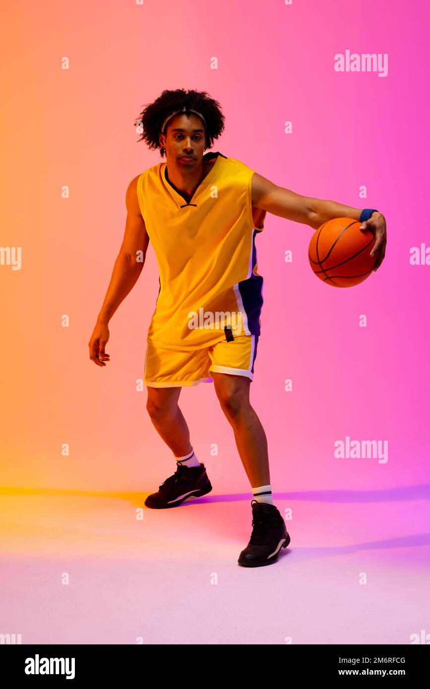 Image of biracial basketball player bouncing basketball on pink to ...