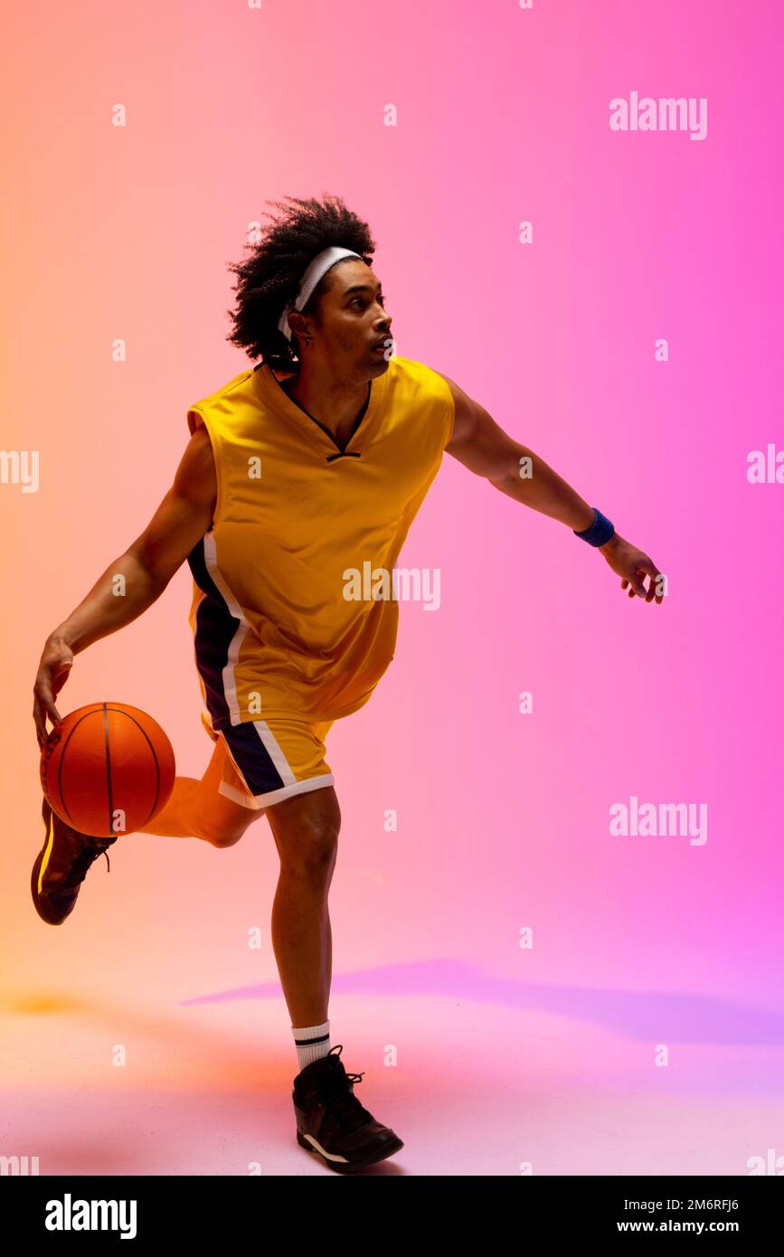 Image of biracial basketball player bouncing basketball on pink to ...