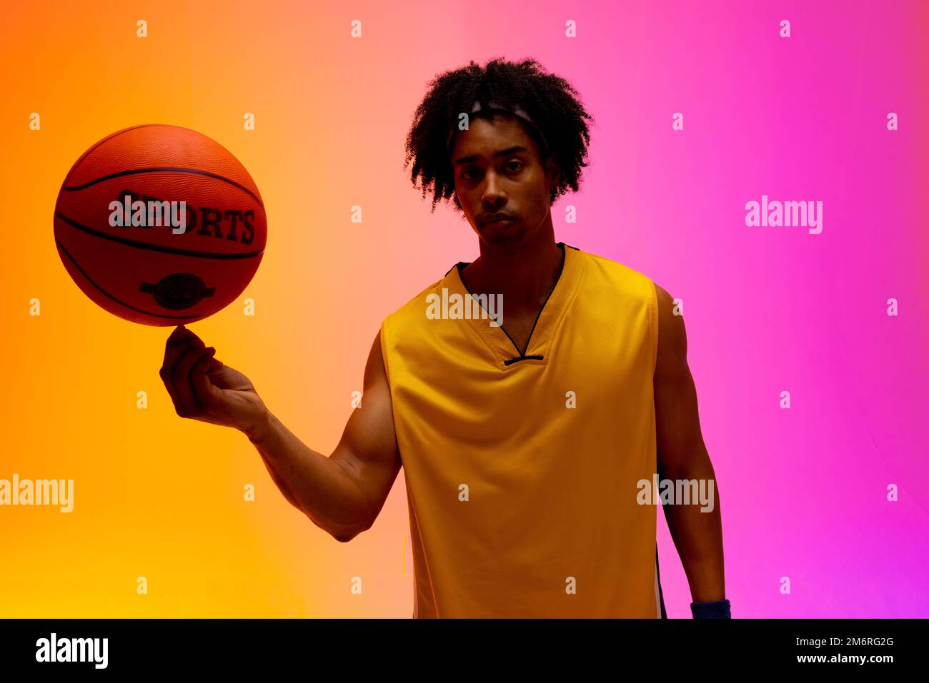 Image of biracial basketball player spinning basketball on pink to ...