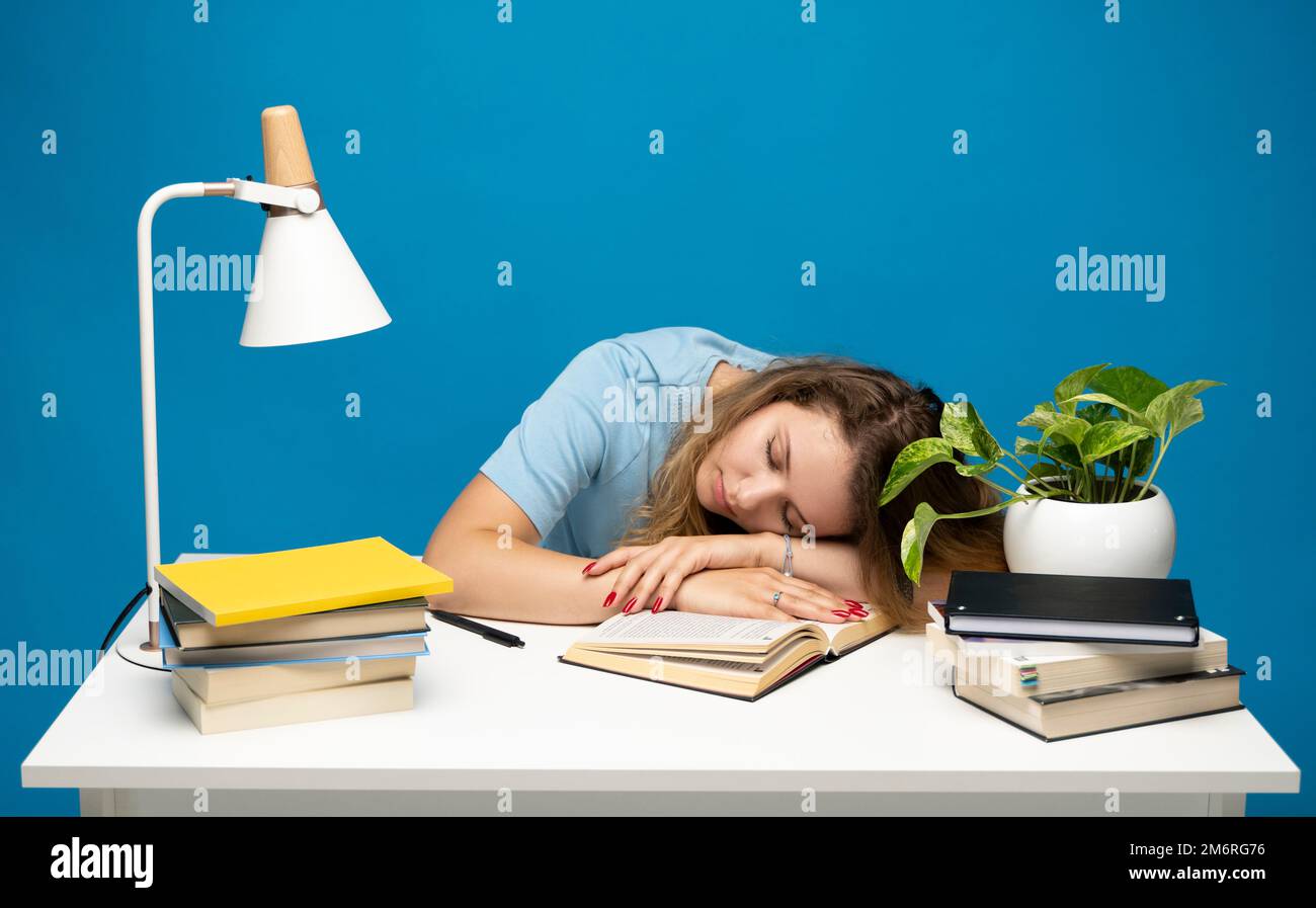 Tired student sleeping at her desk with books while having a lot of ...